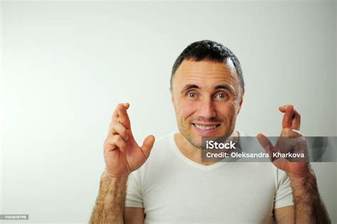 남자는 그것이 이루어지기를 바란다 양쪽 얼굴 근처에 손가락이 교차 된 두 손을 넣어 사람이 속일 때 그는 또한 손가락을 교차 부 자연스러운 미소 기쁨 수줍음 실례합니다 중년