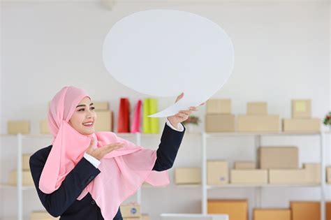 파란 양복을 입은 활동적인 아시아 무슬림 여성이 온라인 패키지 상자 배달 배경으로 하얀 말풍선을 들고 있다 스타트업 중소기업