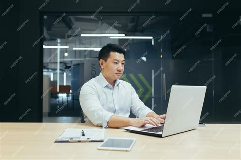 Premium Photo Portrait Of A Successful Young Asian Male Programmer Sitting In A Modern Office