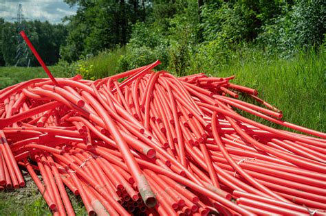 전기 전송을 위해 잔디밭에 놓인 빨간 플라스틱 튜브는 현대적인 인프라 에너지 분배 및 활기찬 야외 환경에서 기술과 자연의 교차점을 보여줍니다 0명에 대한 스톡 사진 및 기타