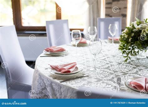 Праздничная сервировка стола с бокалами и свежими цветами Стоковое