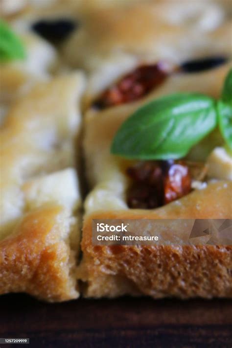 홈메이드 이탈리안 포카치아 빵 덩어리와 슬라이스 그린 올리브 햇볕에 말린 토마토 바질 잎 장식을 곁들인 페타 치즈의 클로즈업