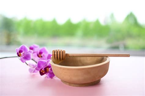 분홍색 배경 개념에 탈약과 아름다움세트 설탕 페이스트 또는 제모 왁싱 녹은 페이스트 오키드 및 여성의 손 특별한 디퍼 스틱이있는 나무 그릇에 설탕 페이스트 또는 꿀 0명에