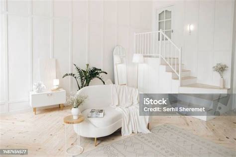 흰색 가죽 소파 플로어 램프 전체 길이의 타원형 거울 2층으로 이어지는 나무 계단이 있는 세련된 흰색 거실 아파트의 계단 집에서 화분에 심은 식물 아무도 0명에 대한 스톡