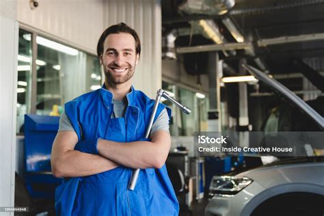 특별한 파란색 가운 유니폼을 들고 파이프 원숭이 렌치차량 서비스 검사에서 카메라를 보고 미소 짓는 젊은 남성 자동차 기술자 정비사 20 24세에 대한 스톡 사진 및 기타