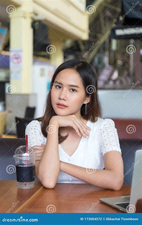 Close Up Smiling Young Asian Woman Sitting In Front Of Laptop On Wooden