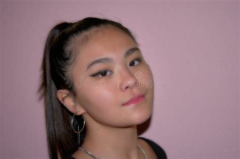 Confident Chinese Girl Posing In Front Of A Pastel Wall Indoors Stock