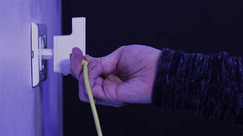 Man Insert WiFi Repeater Into Electrical Socket On The Wall And Plug In A Ethernet Cable Into It