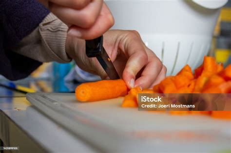 날카로운 칼로 부엌의 커팅 보드에 당근을 작은 조각으로 자르는 사람의 초상화 오렌지 야채는 저녁 식사를위한 멋진 식사에 사용할 준비가되어 있습니다 건강한 생활방식에 대한