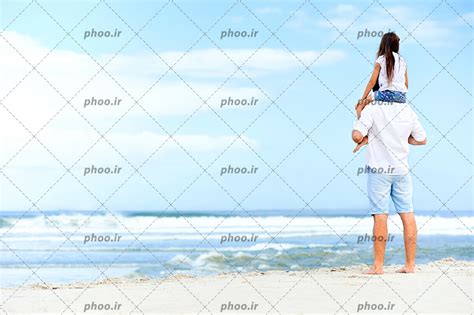 عکس با کیفیت دختر بر روی دوش پدر ایستاده در کنار دریا در حال تماشا کردن