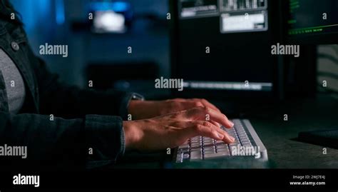 Close Up On Hands Of Female Computer Hacker Sitting In Front Of Screens Breaching Cyber Security