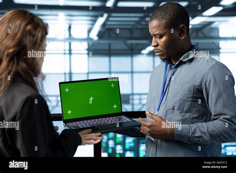 Team Of Engineers Working In Server Farm Using Green Screen Laptop To