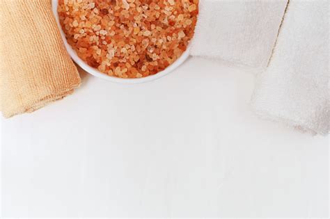 콘크리트 흰색 바탕에 목욕 수건을 압 연 흰색과 오렌지색 솜 털 수건 고 오렌지 향기 바다 소금 목욕에 대 한 스파의 테마입니다 공간에 복사 합니다 3가지 개체에 대한 스톡