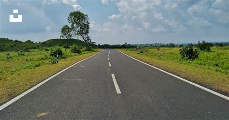 낮에는 흰 구름 아래 푸른 잔디밭과 푸른 하늘 사이의 회색 콘크리트 도로 사진 Unsplash의 무료 가는 길에 이미지