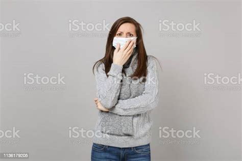 회색 스웨터에 젊은 여자 살 균 얼굴 마스크와 스카프 스튜디오에서 회색 배경에 고립 된 입에 손을 넣어 건강 한 라이프 스타일 아픈 질병 치료 추운 계절 개념입니다 복사