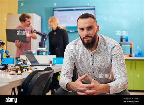 A Man Sitting In A Robotics Laboratory While His Colleagues In The Background Test New Cutting