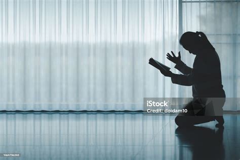 일몰 시간에 현대 교회에서 무릎을 꿇고 기도하는 여자의 실루엣 하느님께 드리는 여성 가톨릭 기도 예배는 믿음으로 새벽에 가정에서 더 나은 삶을 기원합니다 무릎을 꿇고 있는