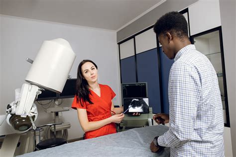 현대 클리닉에서 젊은 여성 백인 의사 태블릿 Pc를 들고 신장과 내부 장기의 그녀의 남성 아프리카 환자 초음파 스캔을 보여주고