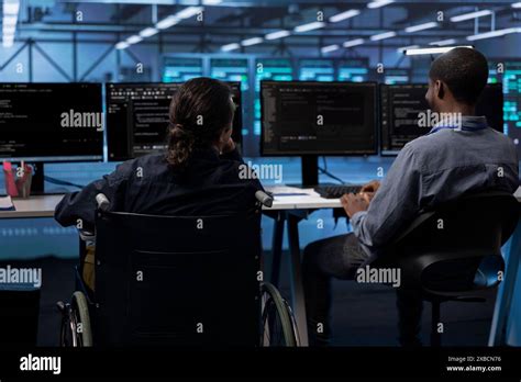 Person With Paraplegia And Colleague Working In Inclusive Server Hub Workspace Typing On Pc