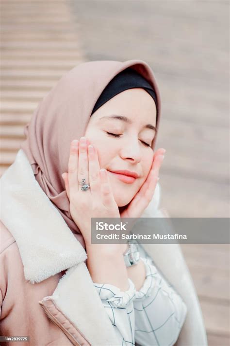 베이지 색 코트와 머리 스카프를 입은 무슬림 여성 공원에있는 세련된 무슬림 여성 벤치에 앉아있는 소녀 20 24세에 대한 스톡 사진 및 기타 이미지 Istock