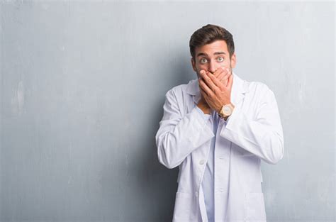잘생긴 젊은 전문 남자 회색 그런 지 벽 입고 위에 흰색 코트 입 실수에 대 한 손으로 다루는 충격된 비밀 개념입니다 가리기에 대한 스톡 사진 및 기타 이미지 Istock