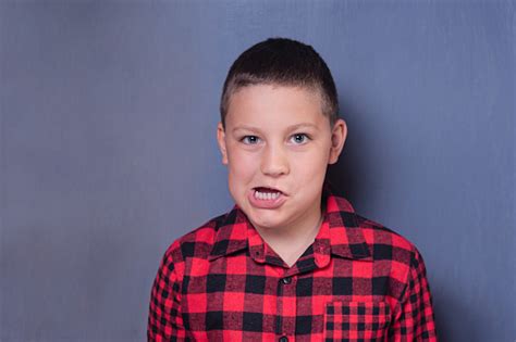 밝은 갈색 머리와 빨간 격자 무늬 셔츠를 가진 쾌활한 유럽 십대 소년은 고립 된 회색 배경에 재미있는 얼굴을 만든다 8 9 살에 대한 스톡 사진 및 기타 이미지 Istock