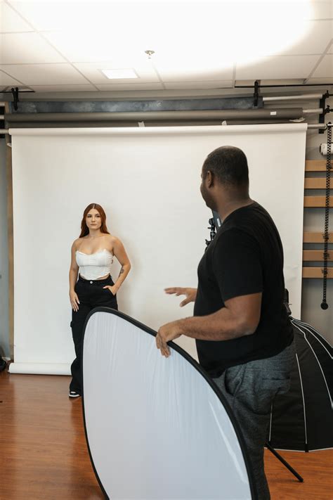 Женщина в красном топе сидит на стуле и позирует перед камерой · Бесплатные стоковые фото