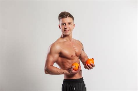 Chico atlético saludable y guapo con un cuerpo musculoso sostiene naranjas alimentos crudos