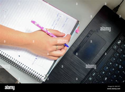 A Top View Shot Of Female Writing Some Notes In A Notebook From A Laptop Stock Photo Alamy