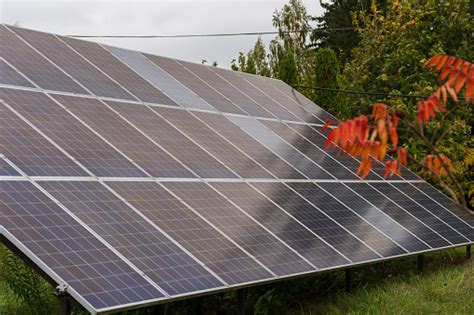 활기찬 정원에 줄지어 서 있는 태양 전지판은 흐린 하늘 아래 햇빛을 흡수하여 지속 가능한 에너지 관행에 대한 약속을 보여줍니다 0명에 대한 스톡 사진 및 기타 이미지