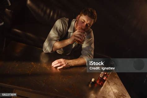 테이블에 위스키 한 잔을 들고 외로운 술에 취한 남자의 따뜻한 파스텔 색상의 분위기있는 초상화 한 남자가 혼자 술을 마십니다 35 39세에 대한 스톡 사진 및 기타 이미지