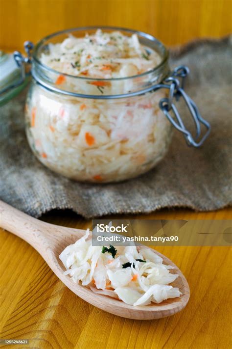 통조림 식품의 개념 노란 배경에 유리 항아리에 허브와 당근과 수제 소금에 절인 양배추 테이블에 나무 숟가락에 자루와 절인 양배추copy Space채식 음식 건강한 생활방식에