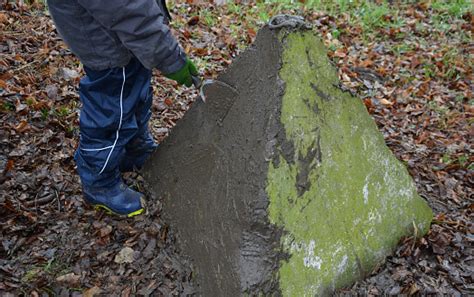 진흙 시멘트 석고와 벽을 던지는에 재생 어린 소년 그들은 아빠에게서 도구를 빌렸습니다 주걱 타일 접착제처럼 진흙을 얼룩 군사 장애물 콘크리트 피라미드 숲에서 가을에 대한