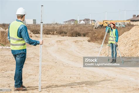 비포장 도로에서 작업하는 디지털 레벨 및 측량 통치자를 가진 측량사 기포수준기에 대한 스톡 사진 및 기타 이미지 기포수준기