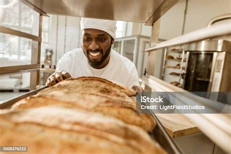 아프리카계 미국인 베이커 제빵 제조에 빵의 신선한 빵을 보고 웃 고 공장 산업 건물에 대한 스톡 사진 및 기타 이미지 공장 산업 건물 남성 모자 모자류 Istock