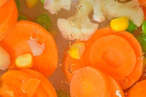 신선한 야채와 함께 끓는 물 클로즈업 물 배경에 당근 완두콩 콜리플라워 옥수수가 있는 수프 야채의 클로즈업 보기 유리 벽에 매크로 거품이 있는 끓는 야채의 질감 평면 디자인