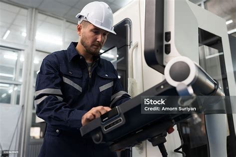 남성 엔지니어가 공장의 모니터에서 Cnc 기계를 제어합니다 공장에서 안전 유니폼과 헬멧을 착용한 선반 기계로 작업하는 남성 공장