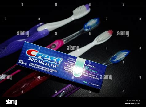 A Row Of Four Toothbrushes With A Packet Of Toothpaste Photographed