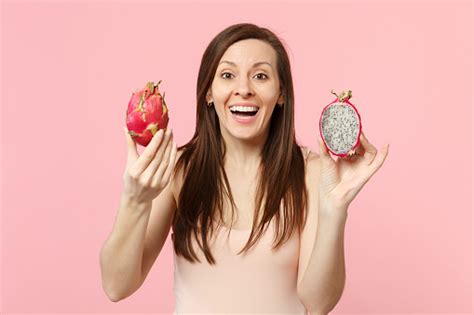 스튜디오에서 분홍색 파스텔 벽 배경에 고립 된 신선한 잘 익은 피타 하 야 용 과일의 두 Halfs 손을 잡고 젊은 여자를 웃 고 사람들은 생생한 라이프 스타일 휴식 휴가