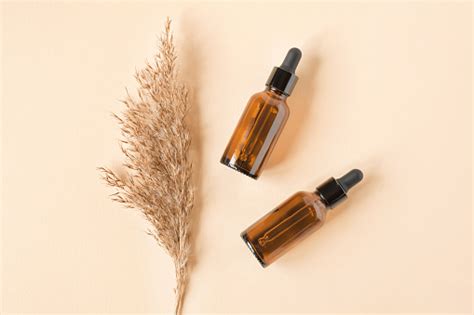 베이지 색 배경에 어두운 호박색 유리 병 팜파스 잔디 자연 스킨 케어 Spa 뷰티 제품 디자인 미네랄 유기농 오일 화장품 최소한의 모형 기름진 피펫 얼굴과 몸 치료 플랫
