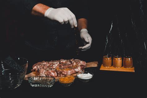 흰색 장갑을 낀 셰프는 돼지고기 조각을 향신료로 문지르고 카레 바질 소금을 사용하고 바비큐에 고기를 양념합니다 고급에 대한 스톡