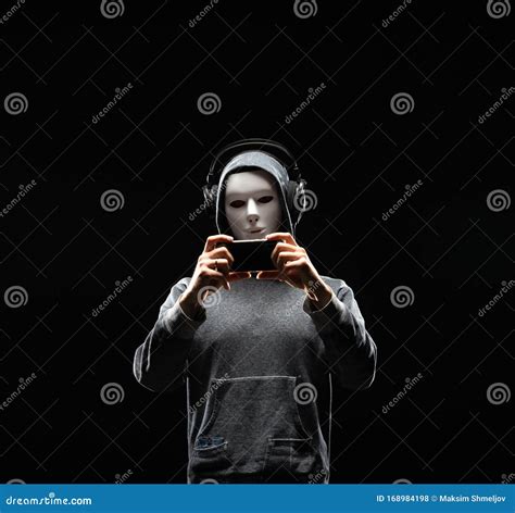 Computer Hacker In White Mask And Hoodie Obscured Dark Face Stock