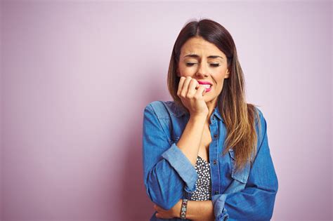 젊은 아름다운 여자는 분홍색 고립 된 배경 위에 서 스트레스와 손톱을 물고 손톱에 손을 긴장 찾고 불안 문제 갈색 머리에 대한 스톡 사진 및 기타 이미지 Istock