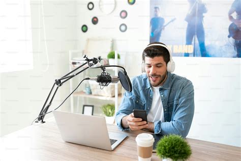 남성 라디오 진행자이자 블로거가 라이브 쇼 중 스마트폰으로 소셜 미디어에서 팬들의 댓글을 읽고 있다 사진 Unsplash의 라디오 이미지