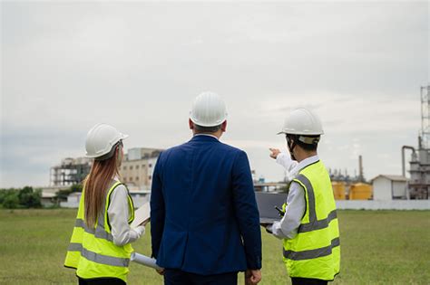 건설 현장에서 향후 개발을 계획하는 엔지니어와 함께하는 관리자 안전 장비를 착용하고 서류를 들고 있는 세 사람 25 29세에 대한 스톡 사진 및 기타 이미지 Istock