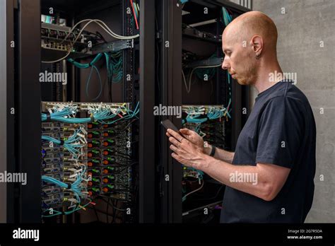 Man Data Center Technician Performing Server Maintenance Using Mobile Phone To Troubleshooting