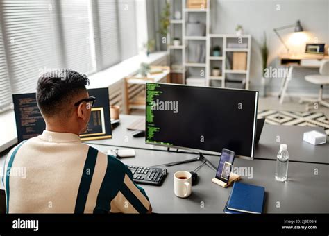 back view of male it developer typing on keyboard with programming code