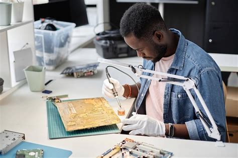 Premium Photo Black Man Fixing Circuit Board With Soldering Iron In Computer Repair Shop
