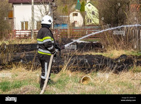 Spring Fire Burning Dry Grass Near Buildings In The Countryside