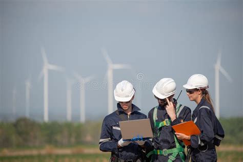 Team Of Engineers Working And Using A Computer Laptop On Site In Wind Turbine Farm Wind